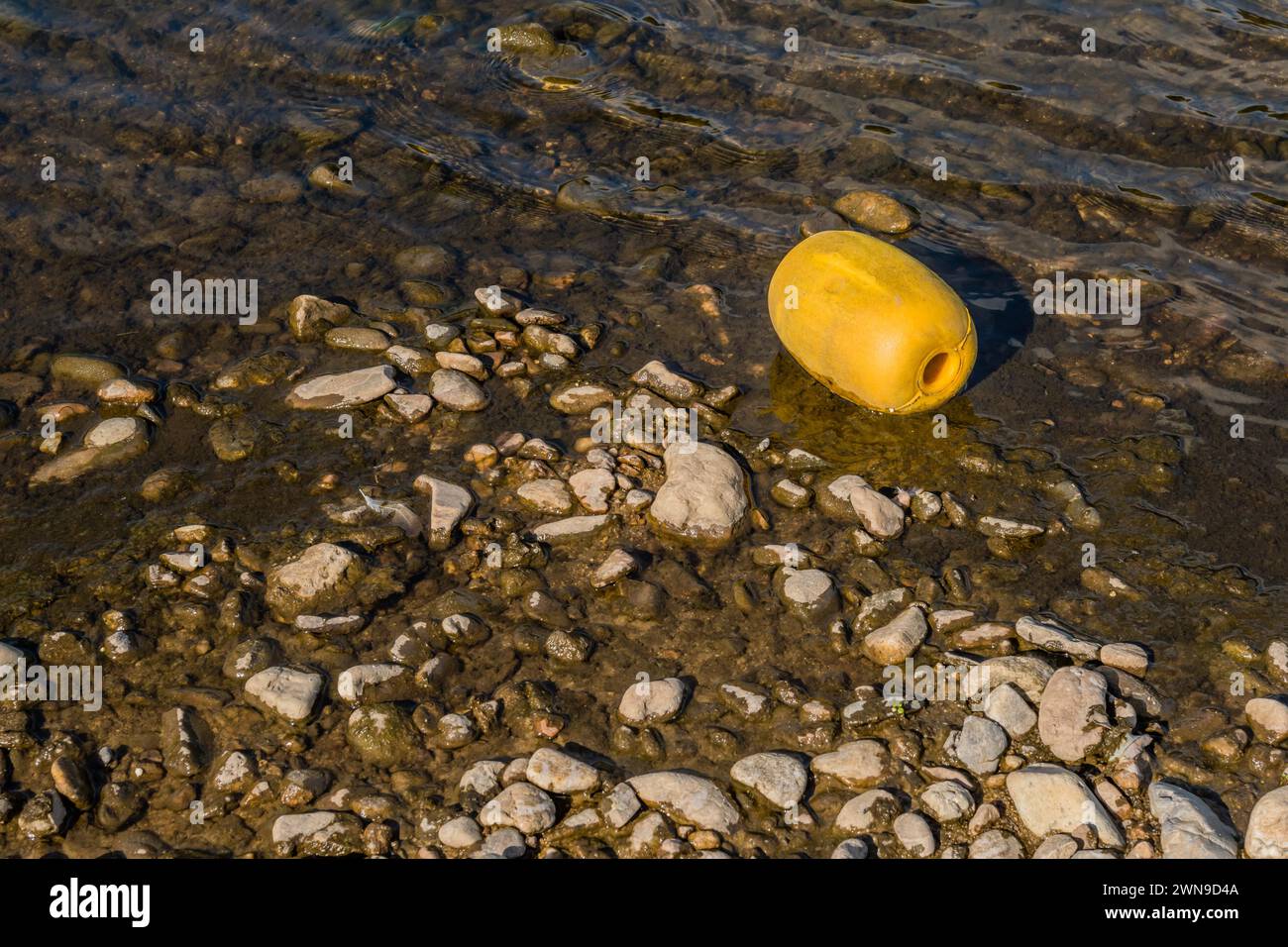 Closeup of large yellow Styrofoam buoy in shallow water beside ...