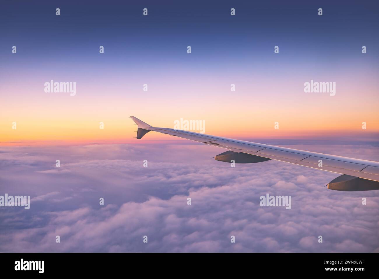 Airplane flying over color sky clouds during scenic sunset or sunrise ...