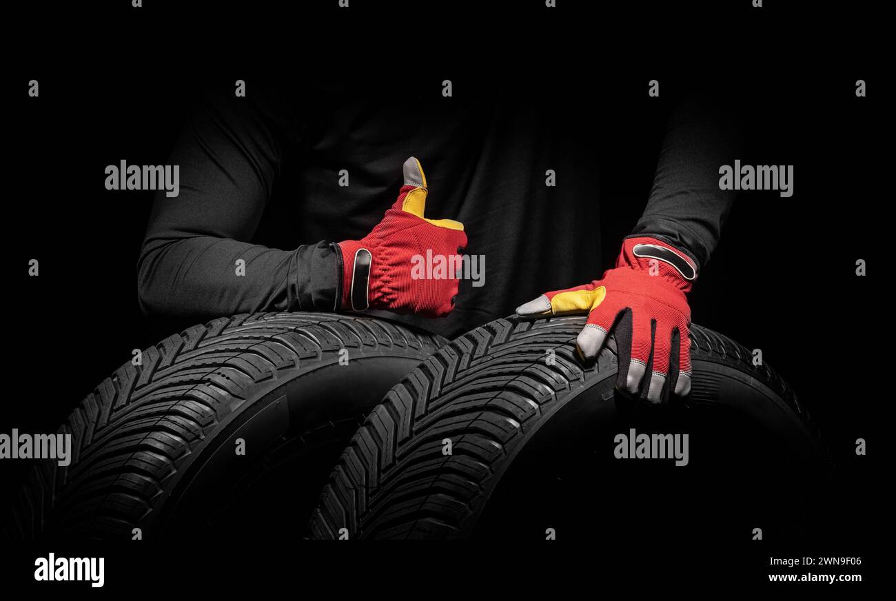 Car tire service and hands of mechanic holding new tyre on black ...