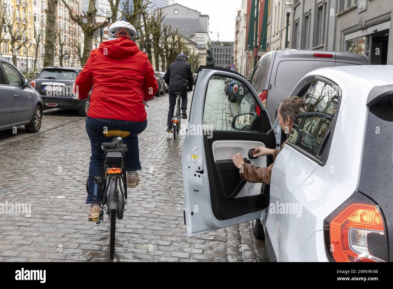 A car driver opens the door of his car with the 'Dutch reach', as a ...