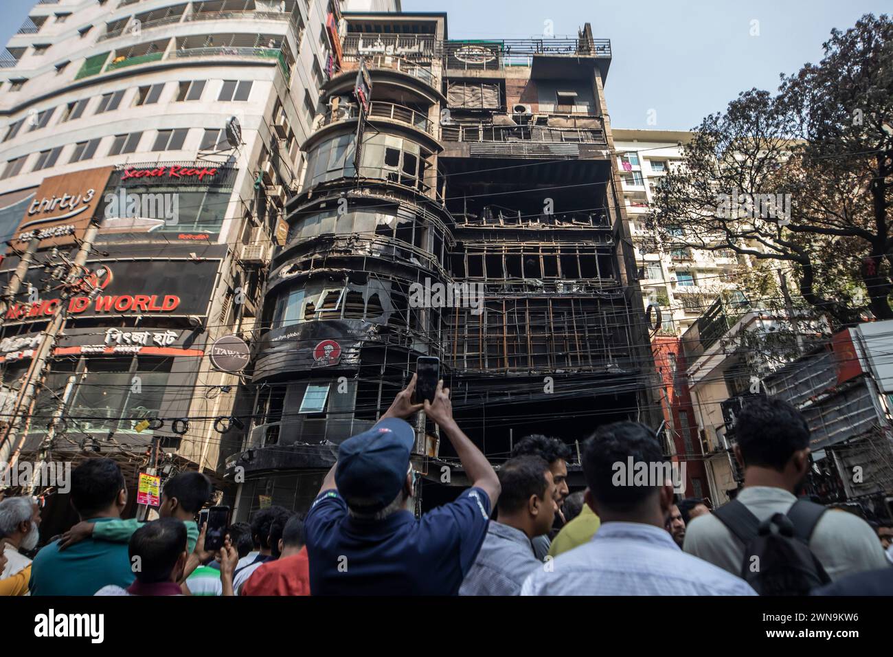 People take photos in front of the multi storey building during the aftermath. At least 46 ...