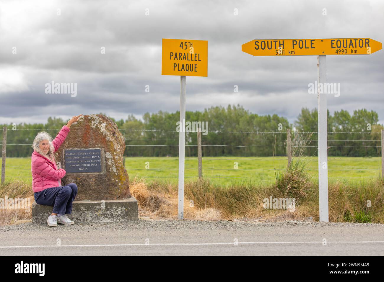 A tourist sits by a plaque marking the 45th parallel near Hilderthorpe ...