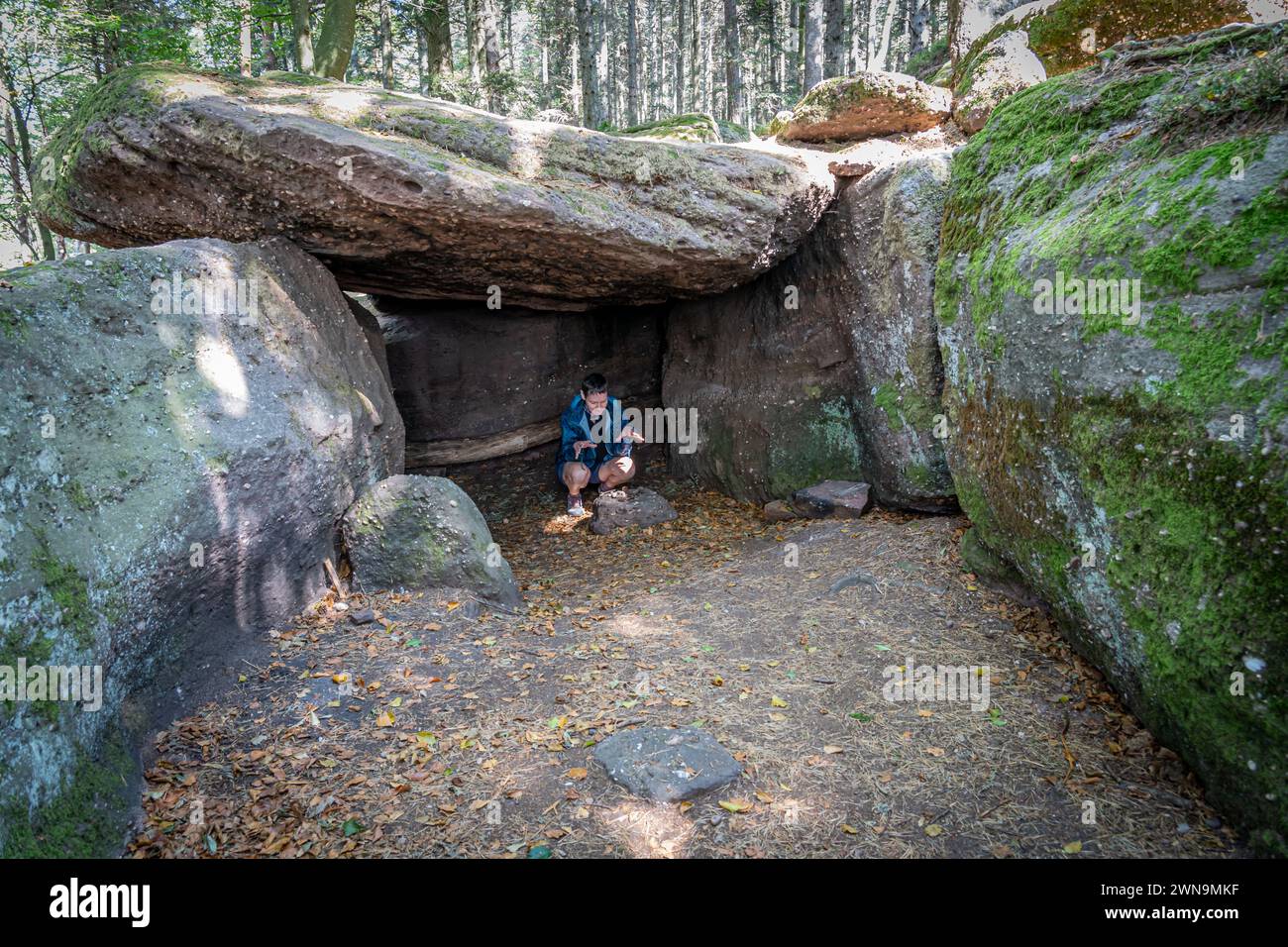 Path of the Gauls. View of a hiker woman sitting in the druids' cave ...