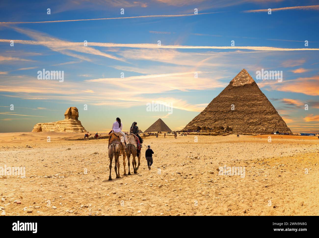 Tourists on camels with bedouin in front of the Great Pyramids of Egypt ...