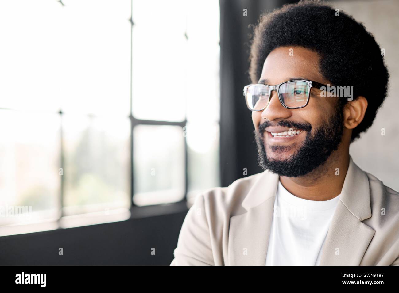 Brazilian young businessman in glasses and afro hairstyle looks aside ...