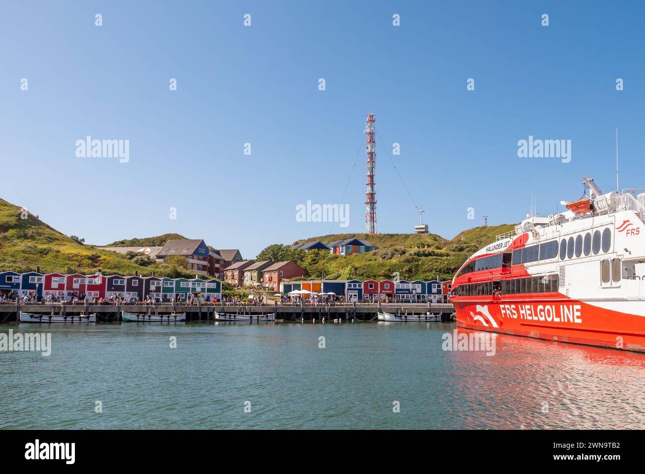 Promenade with wooden lobster shacks and ferry in harbour of Helgoland ...