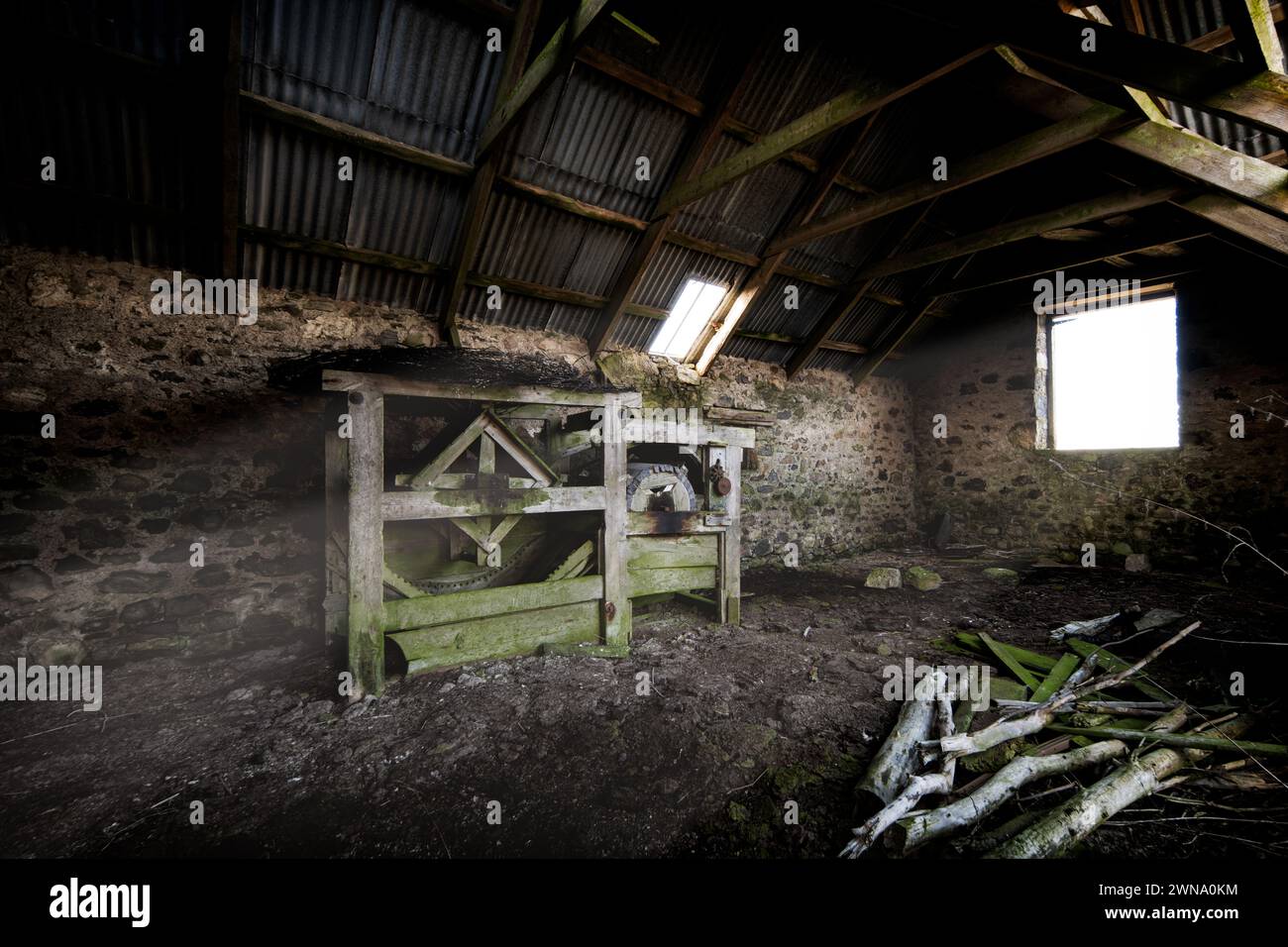 An old threshing machine sits abandoned and forgotten in an old barn high on the hills in the ...