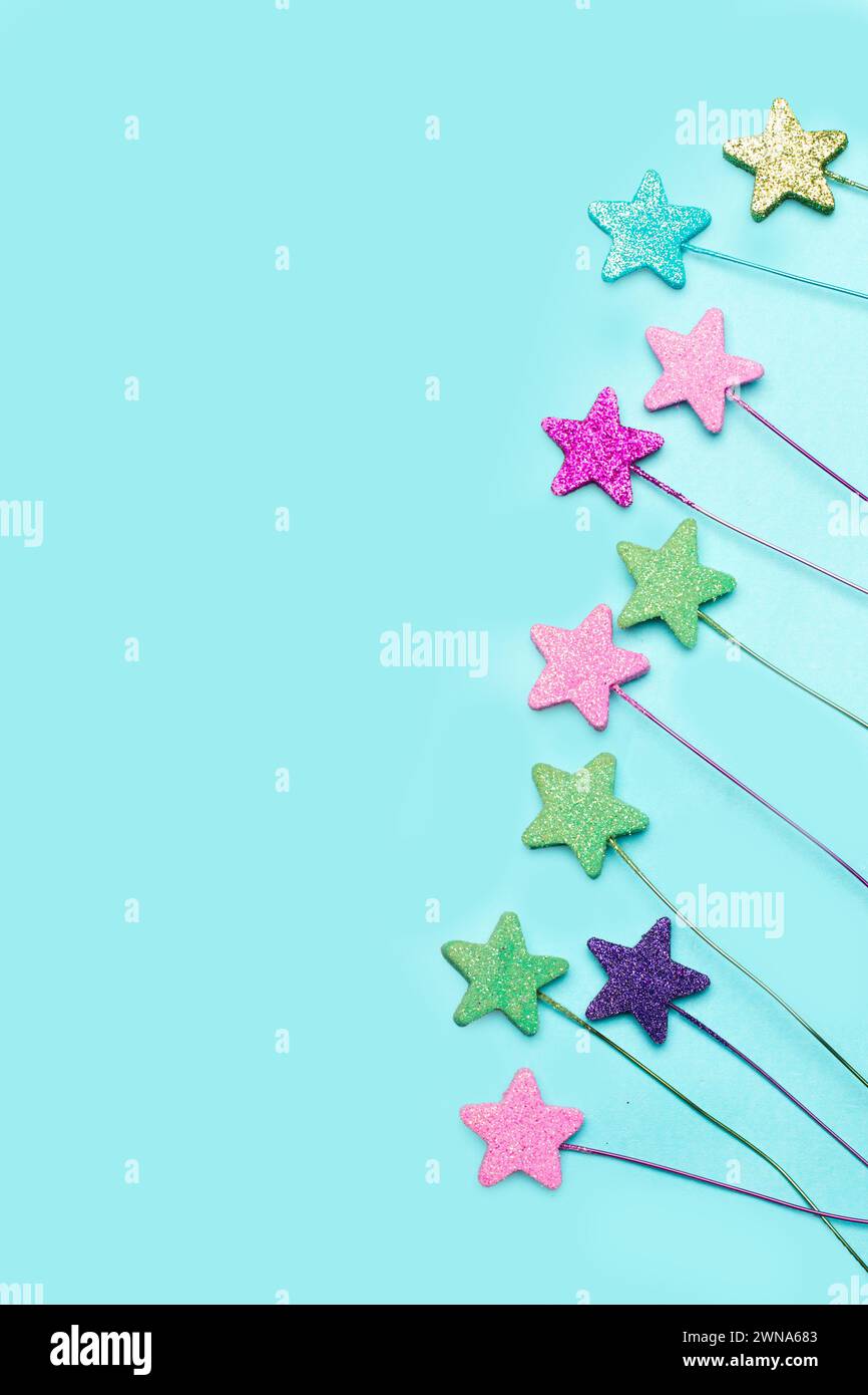 Shiny colored decorative stars on a light blue background with copy ...