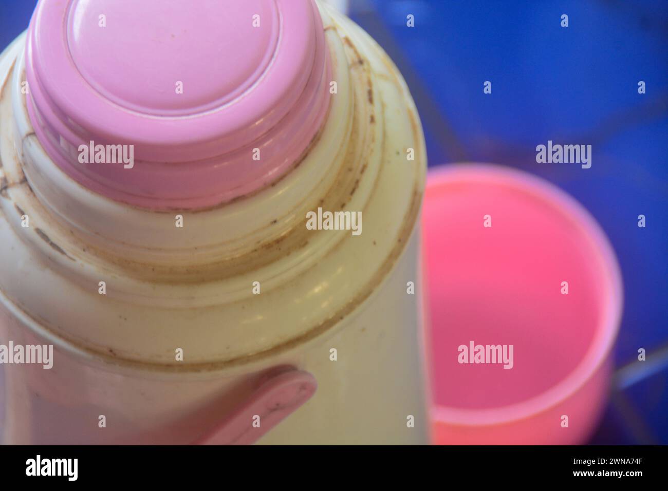 close up view of the thermos with a light brown body color and pink lid ...