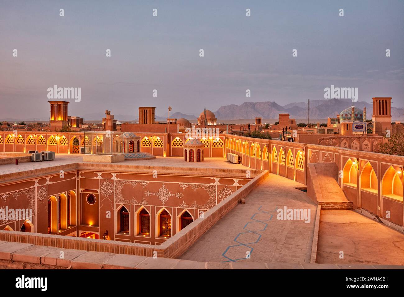 Rooftop view of old adobe buildings illuminated at dusk in the ...