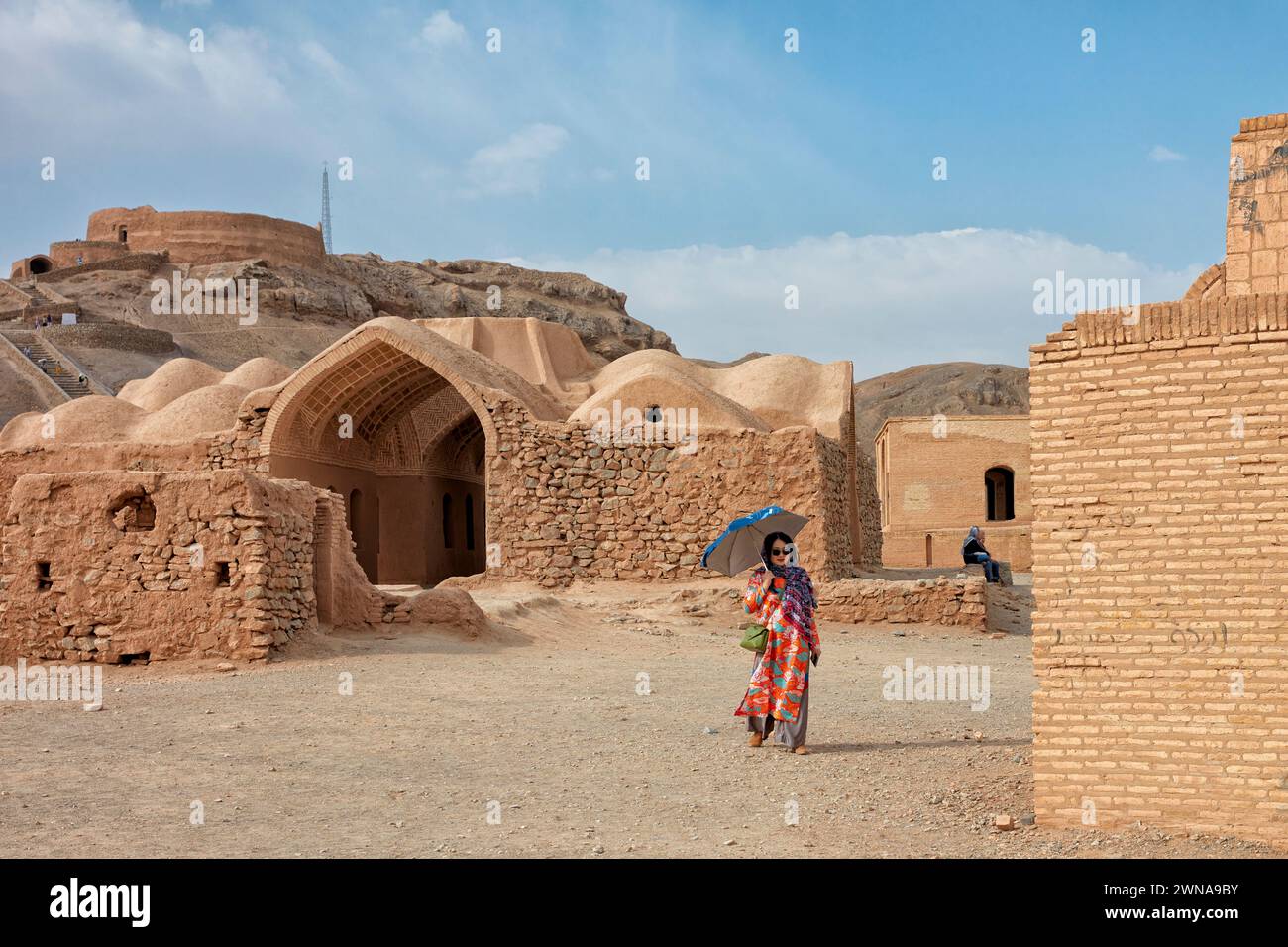 Woman with sun umbrella walks at the Zoroastrian Towers of Silence ...