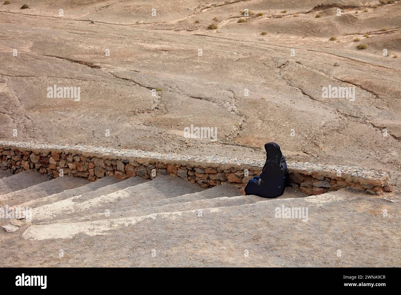 A woman in black chador sits on the stair leading to the Tower of ...