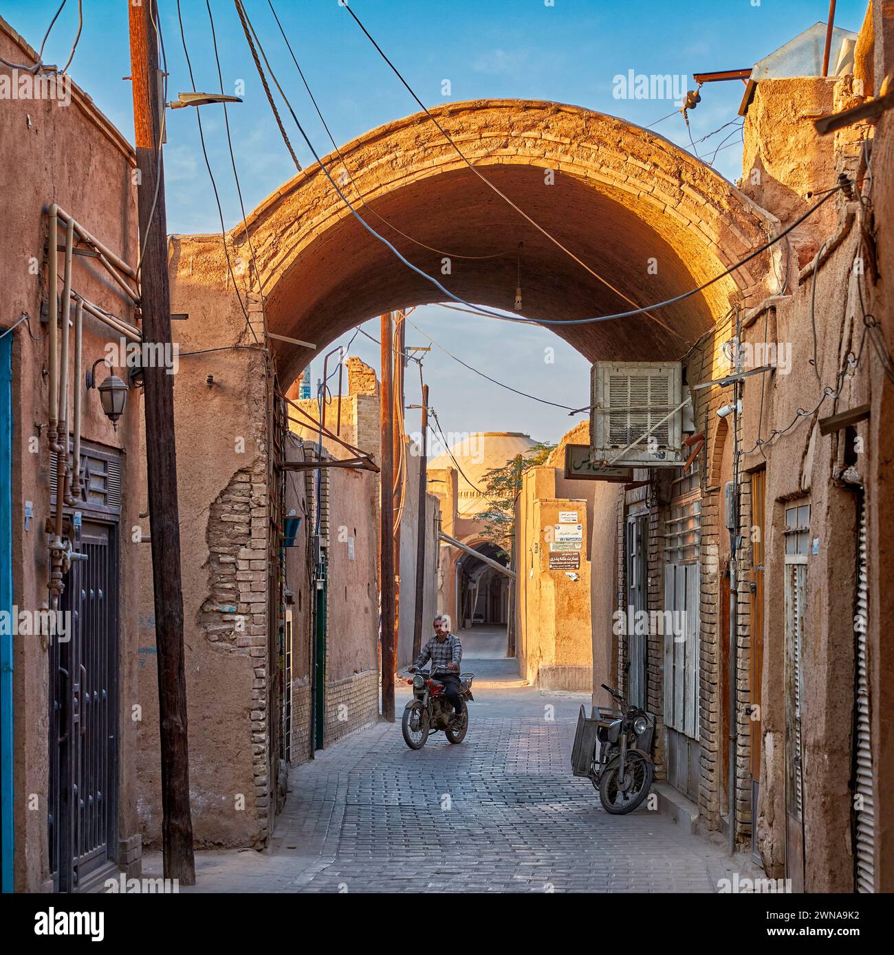 A man on motorbike rides in a narrow street through an archway in the ...