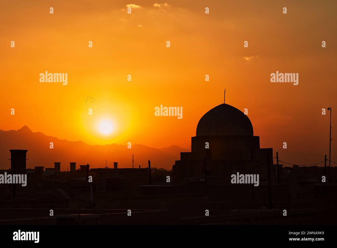 Silhouette of a traditional domed building against setting sun and ...