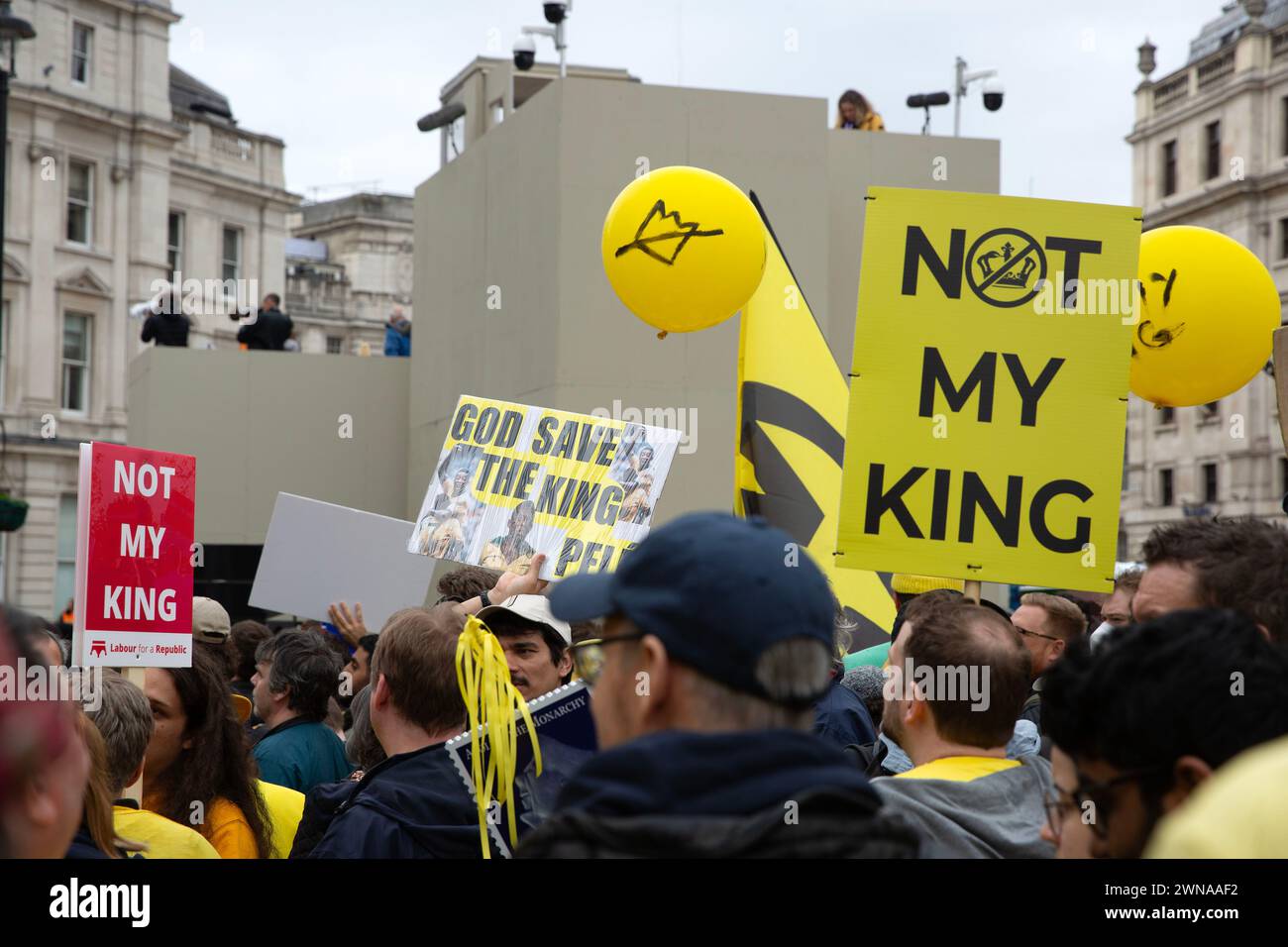 Anti-monarchy placards are held as people gather to view the coronation ...