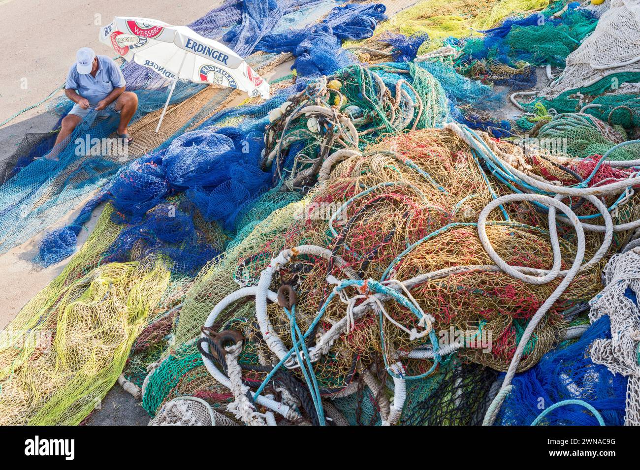 Net patcher in the harbour of Cala Ratjada, Mallorca Stock Photo - Alamy