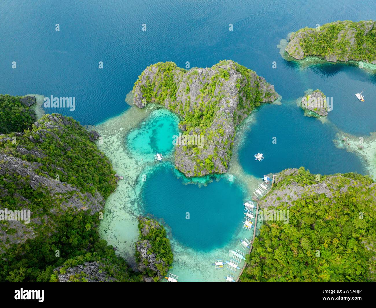 Lagoons with corals. Boats over turquoise water in Kayangan Lake. Coron ...