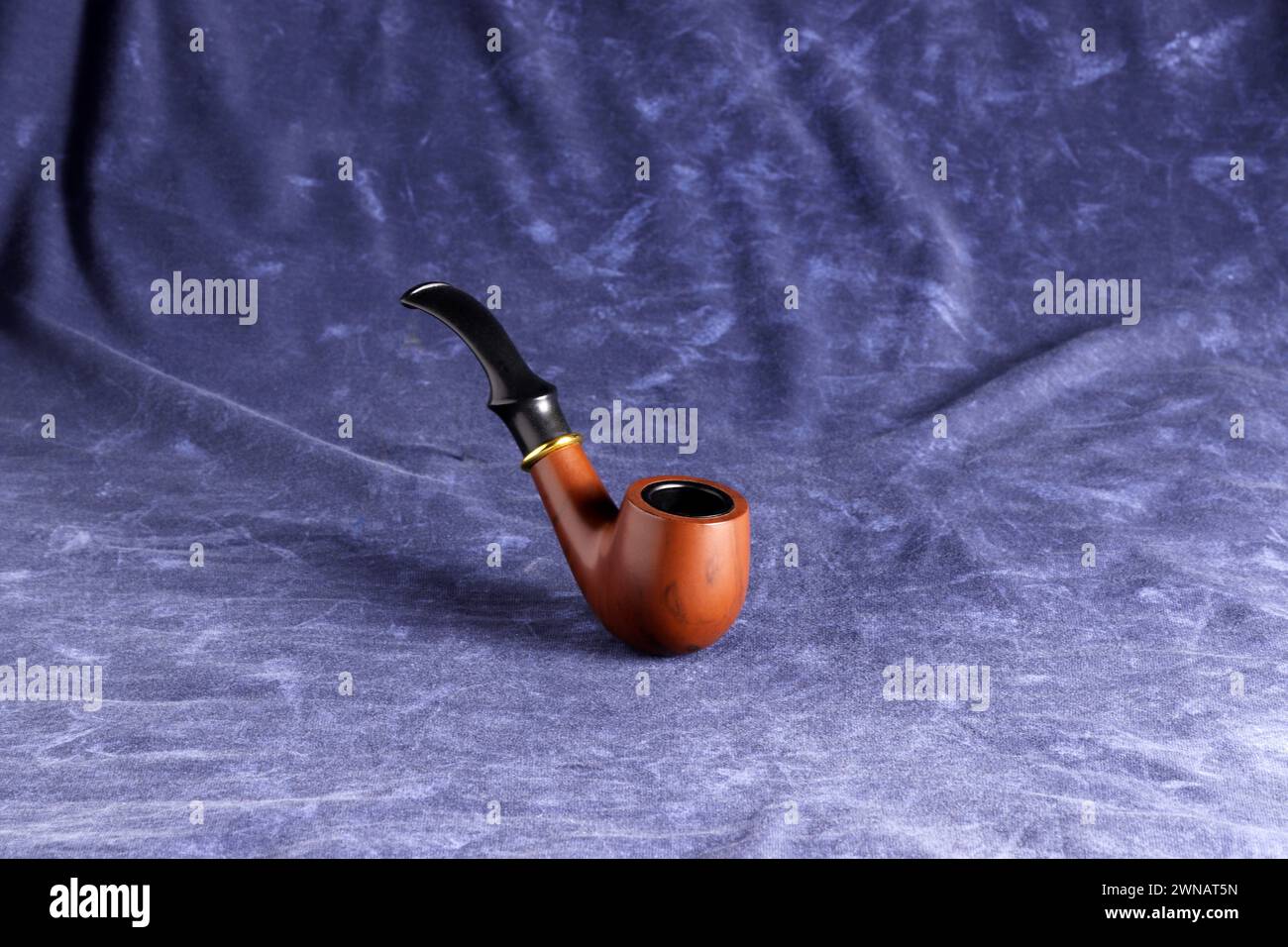 Smoking black-brown pipe on a blue background Stock Photo - Alamy