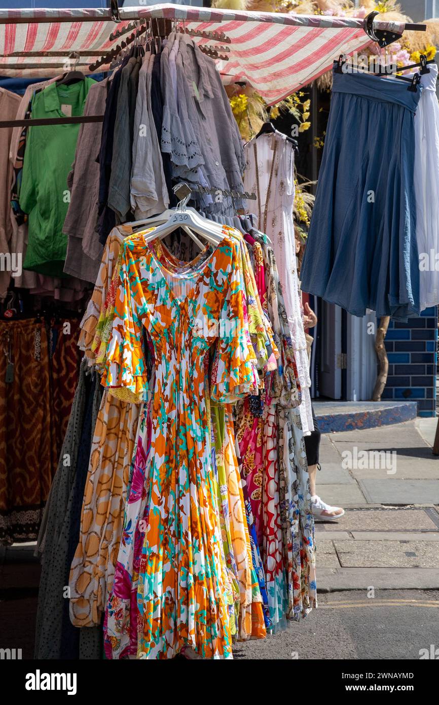 Brightly colored dress and other clothes hanging on rack in Portobello ...