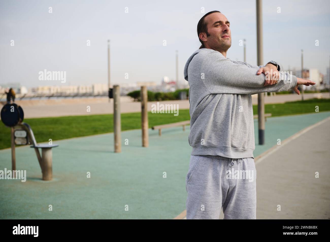Young adult athletic man exercising outdoor, warming up his body before ...