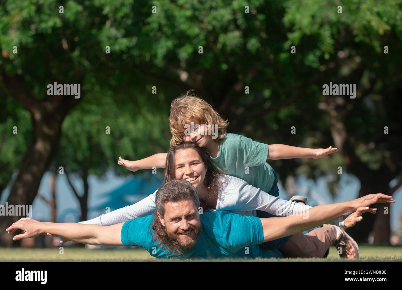 Family lying on grass in park. Parents giving child piggybacks in ...