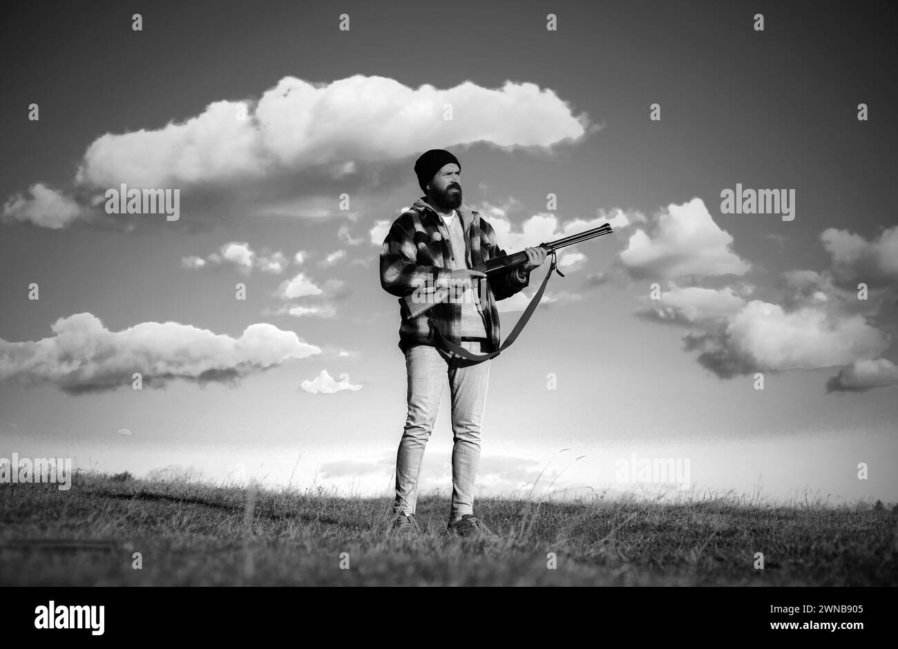 Bearded hunter man holding gun and walking in forest. Hunter with ...