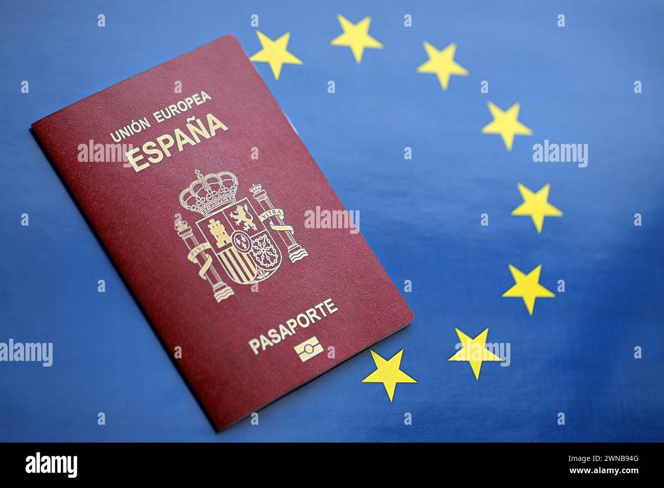 Red Spanish passport of European Union on blue flag background close up ...