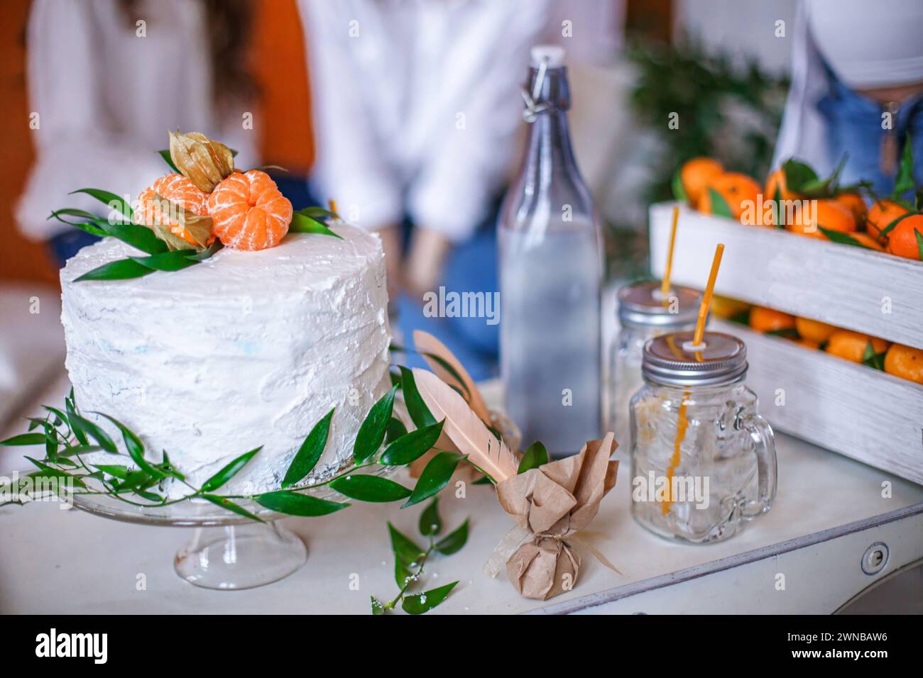 Cream cake decorated with fresh tangerines and leaves at a themed party ...