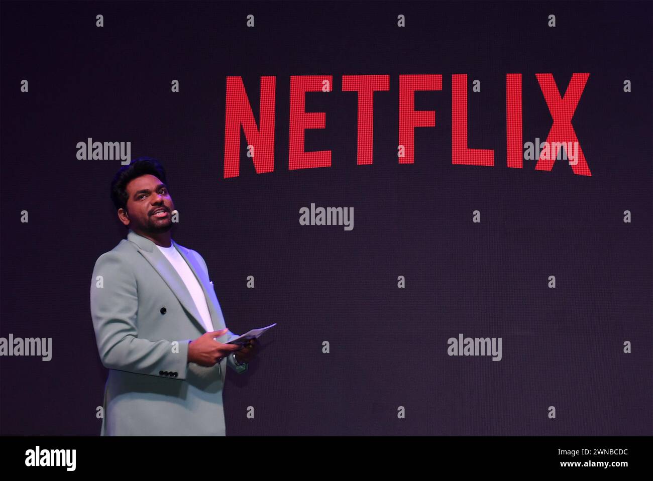 Indian comedian and poet Zakir Khan, stands near the Netflix logo ...