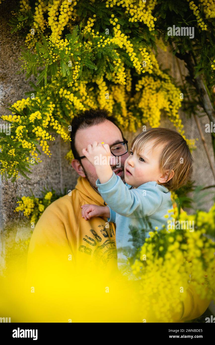 little girl sitting in arms of her father and playing with blooming ...