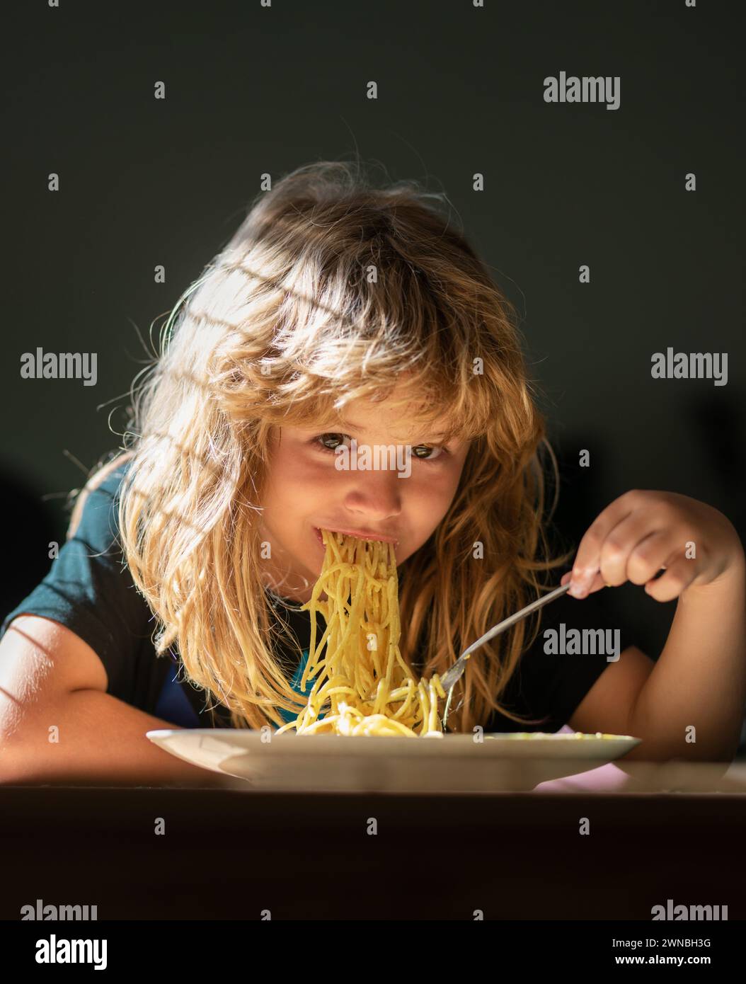 Happy child boy with spoon eats itself. Cute little kid eating ...