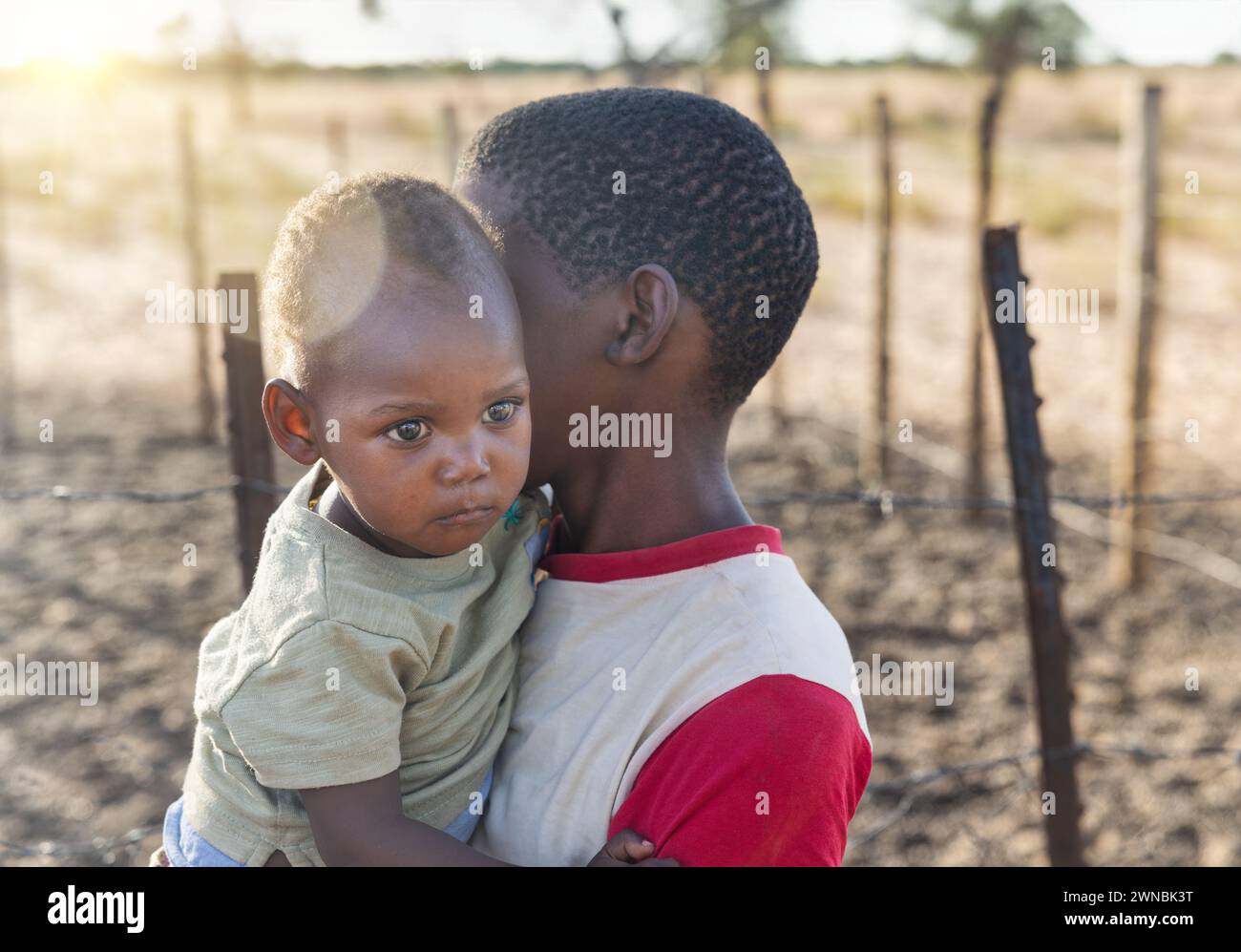 african kid held by his brother at sunset , in the village, standing in ...
