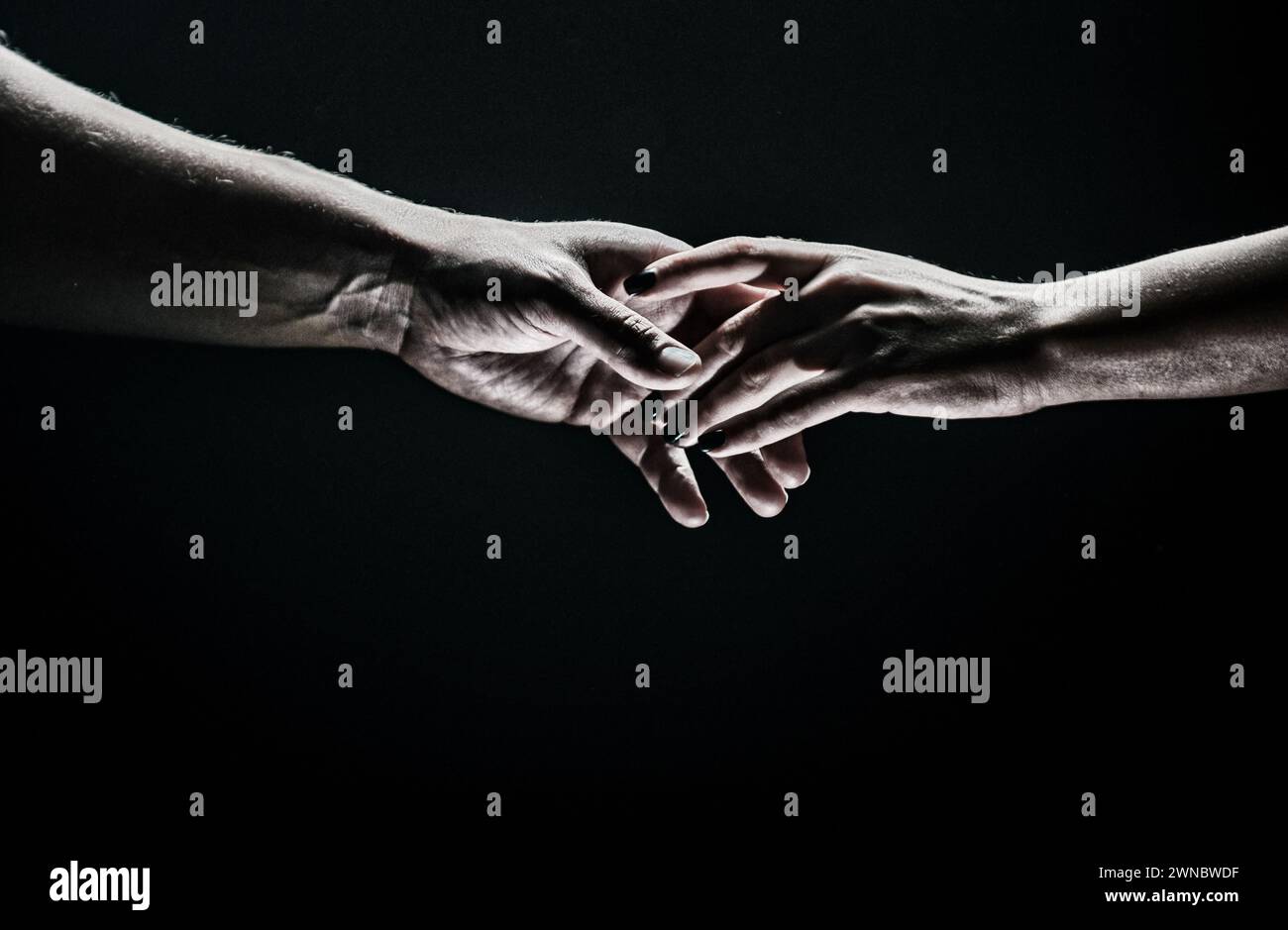 Two hands stretch each other, black background. Couple in love holding ...