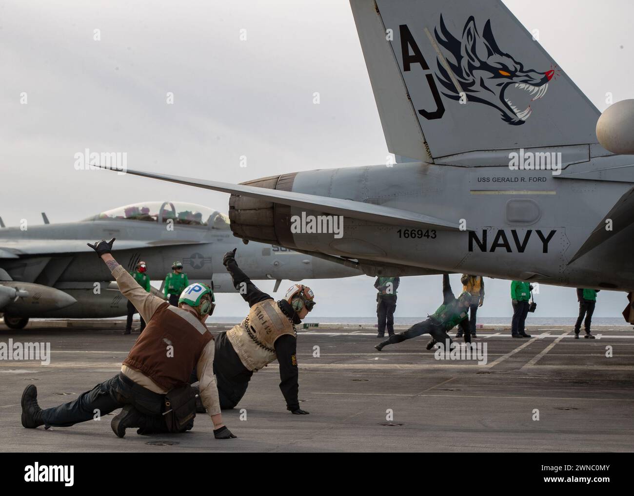 Sailors assigned to the “Gray Wolves” of Electronic Attack Squadron (VAQ) 142 signal for the ...