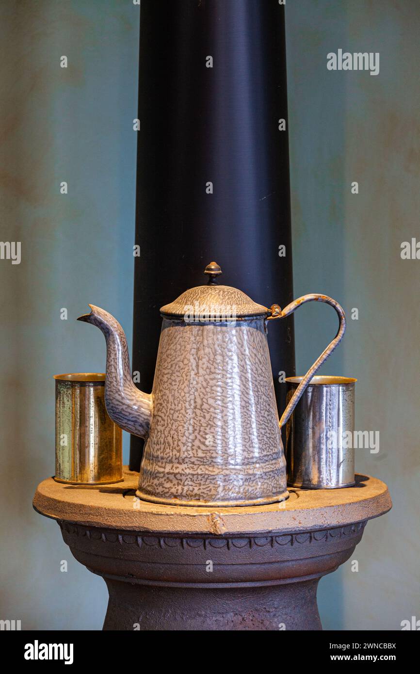 Coffee can and tin cups resting on a heritage coal-fired heating stove ...