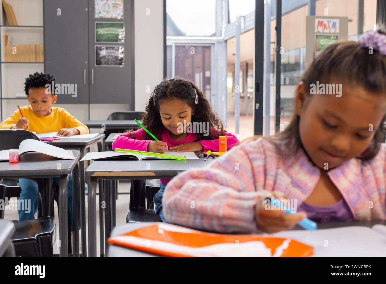 African American boy and two biracial girls focused on their schoolwork ...