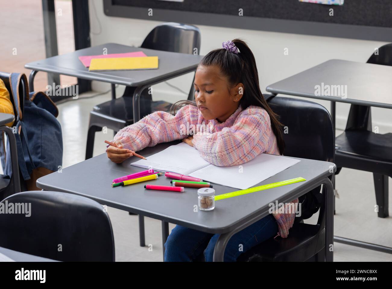 Biracial girl focused on drawing in a school classroom setting Stock ...