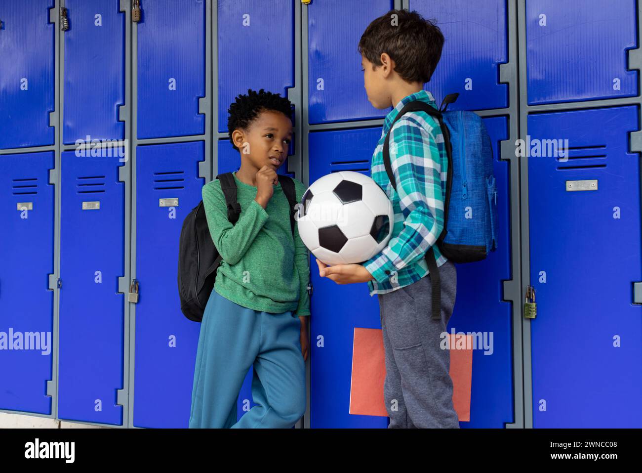 Biracial boy with a soccer ball talks to an African American boy by ...