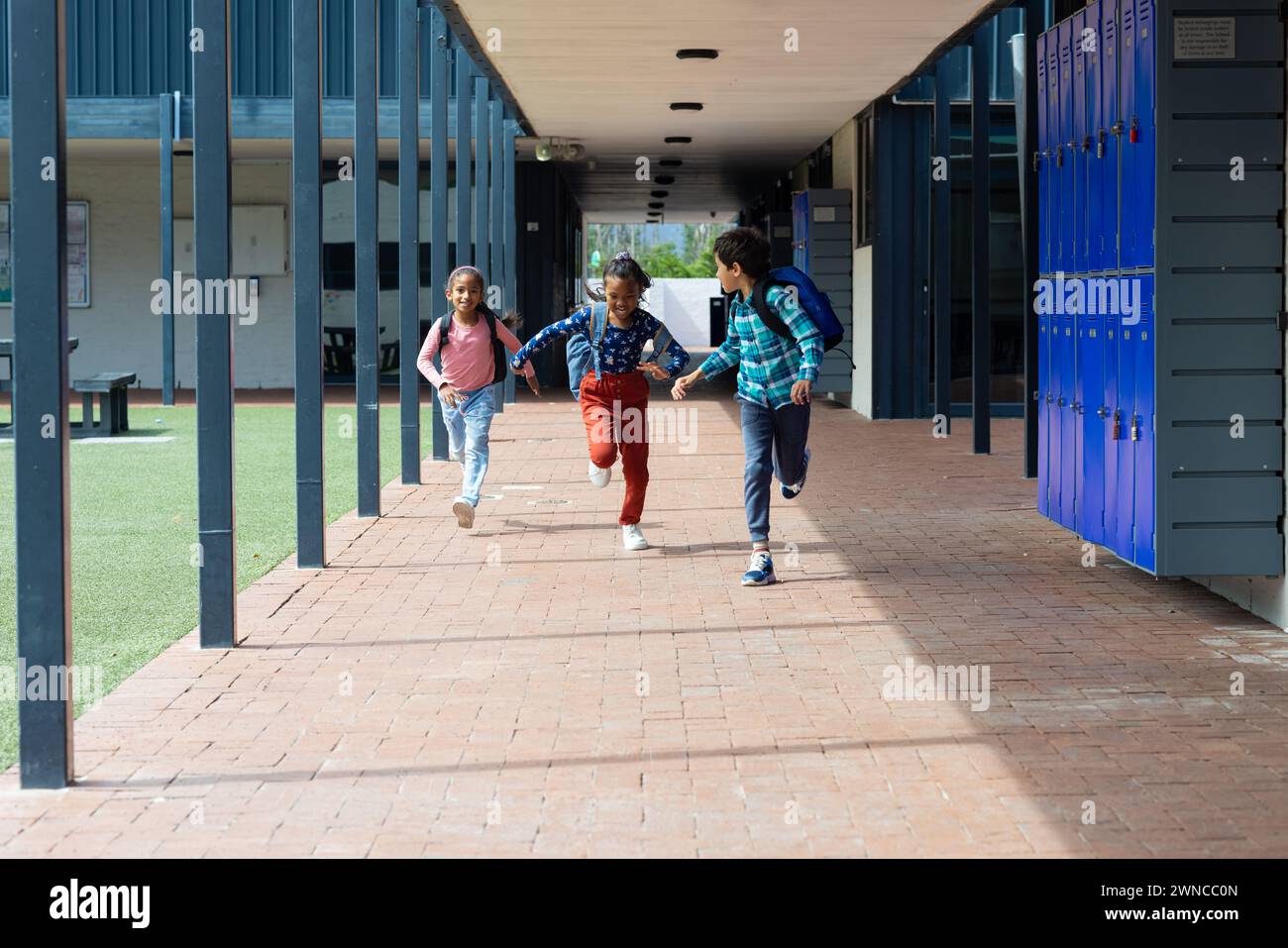 Biracial boy and girl run joyfully with another child through a school ...