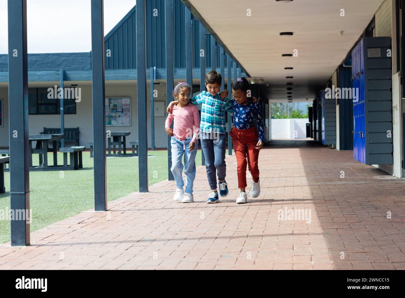Three biracial children are walking together at school with copy space ...