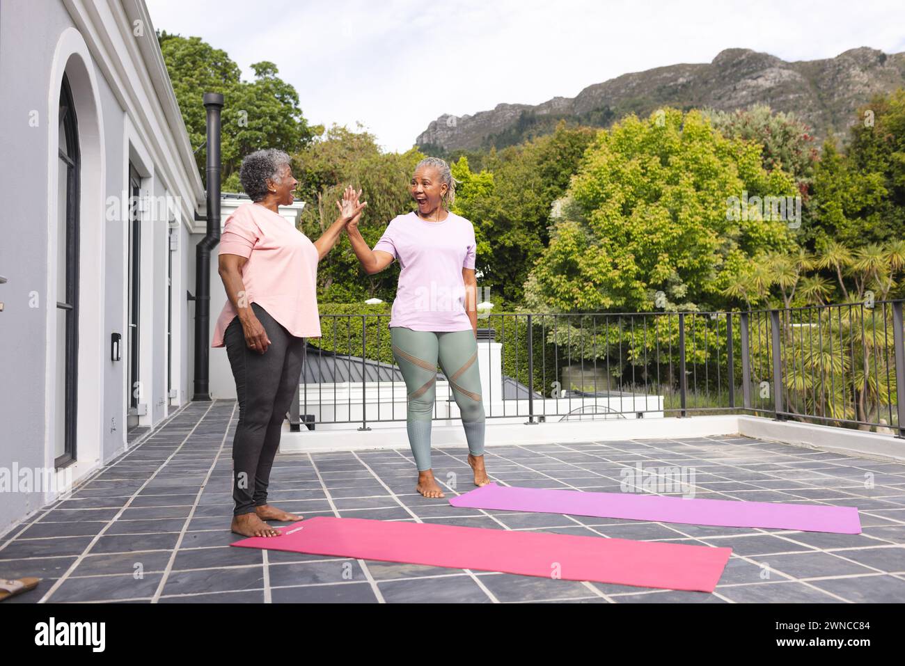 Senior African American woman and biracial woman high-five during yoga ...
