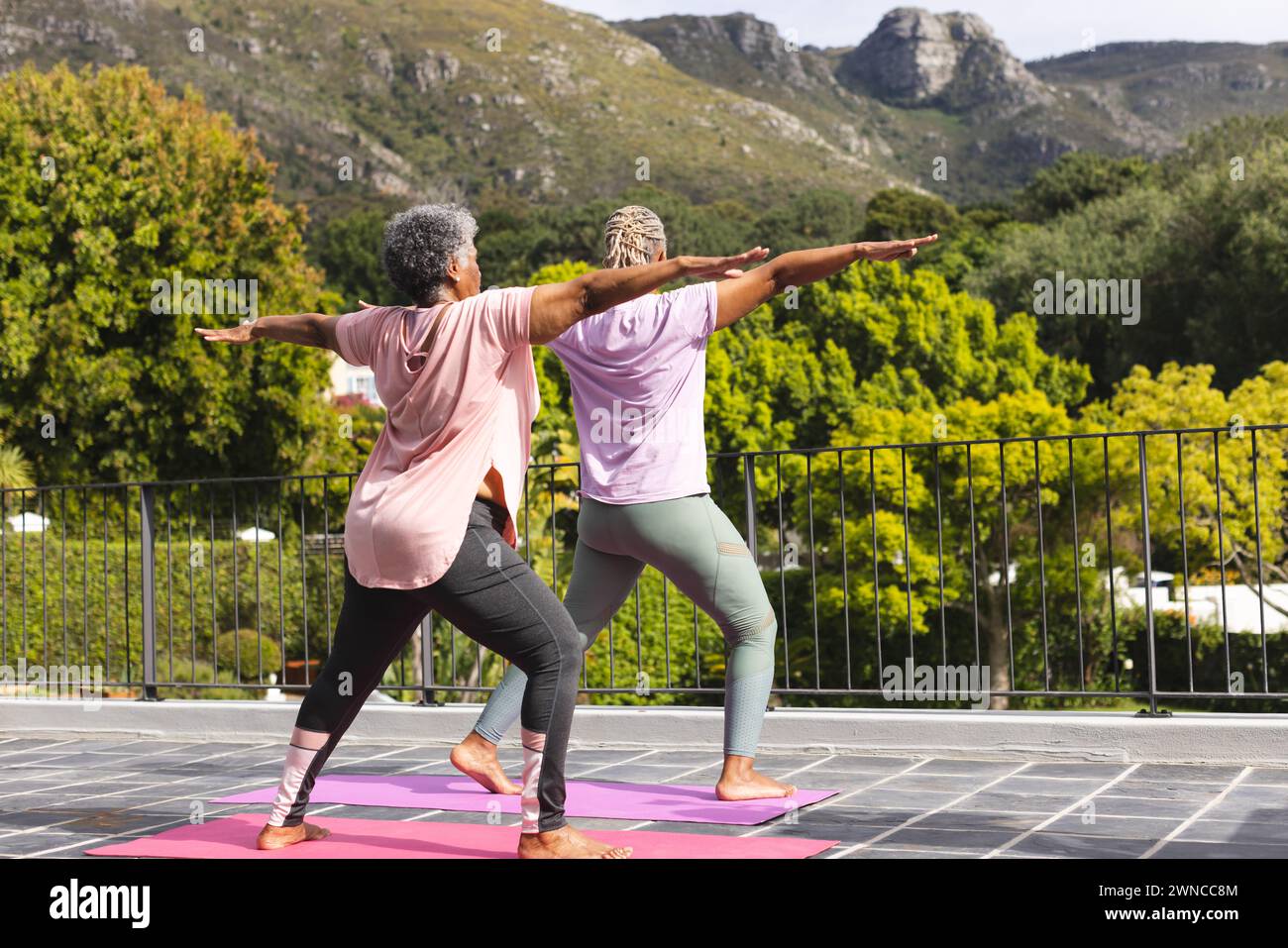 Senior African American woman and senior biracial woman practice yoga ...
