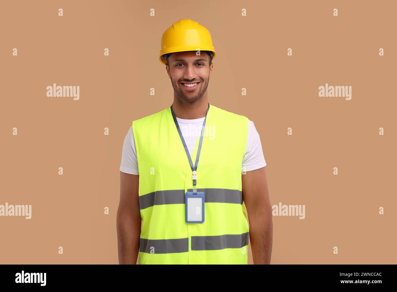 Engineer with hard hat and badge on beige background Stock Photo - Alamy