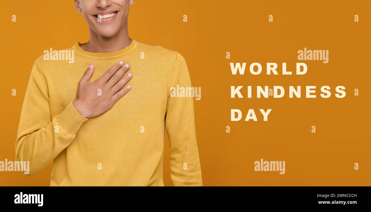World Kindness Day. Grateful man pressing hand to chest on orange ...