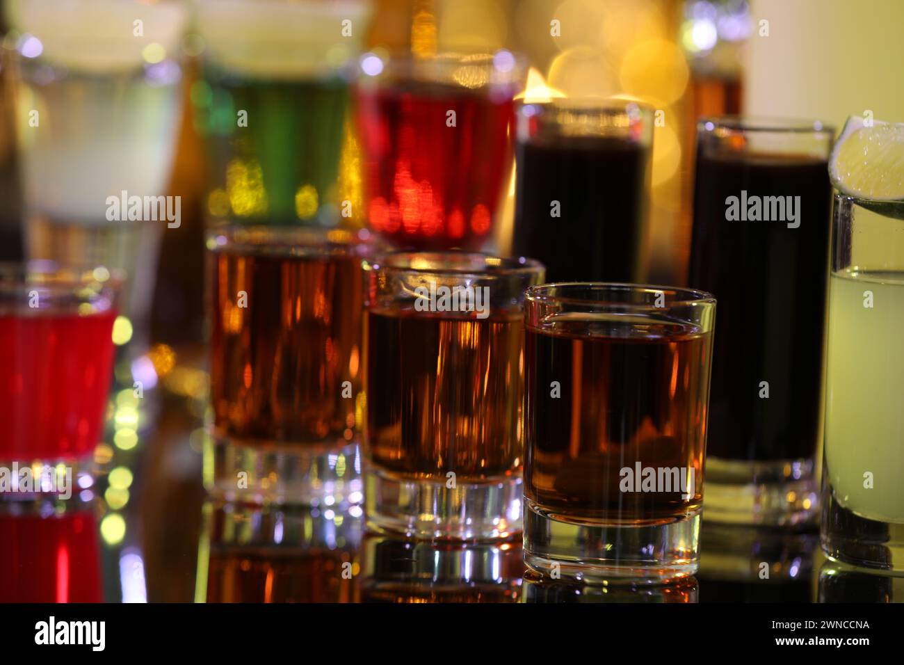 Different shooters in shot glasses on mirror surface against blurred ...