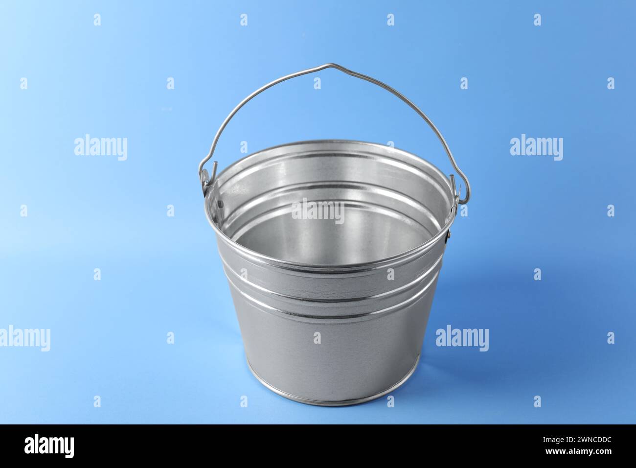 One shiny metal bucket on light blue background Stock Photo - Alamy