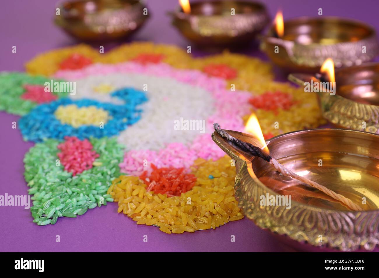 Diwali celebration. Diya lamps and colorful rangoli on purple ...
