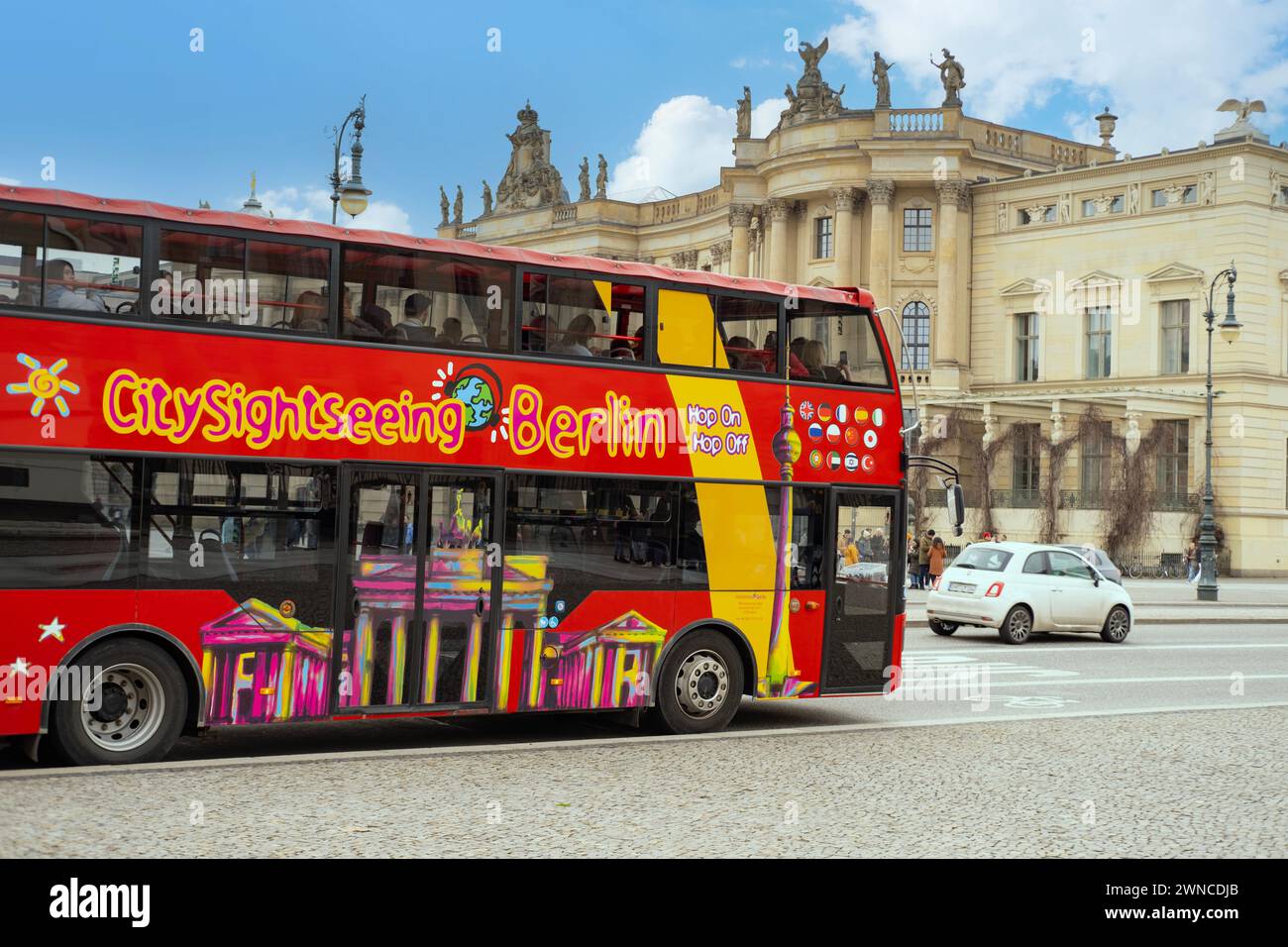 red open-top tourist bus, full of tourists driving through streets of ...