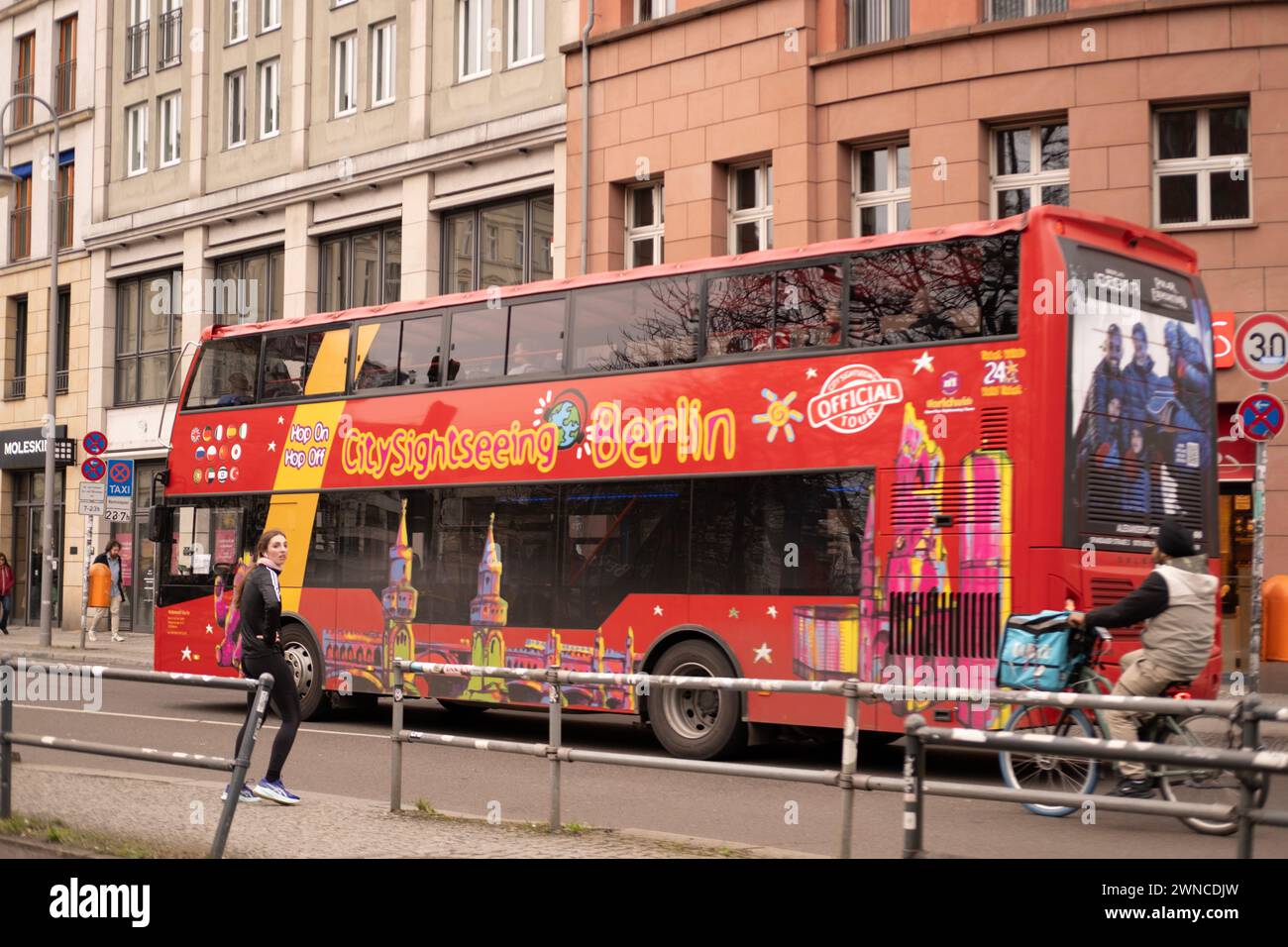 red open-top tourist bus, full of tourists driving through streets of ...