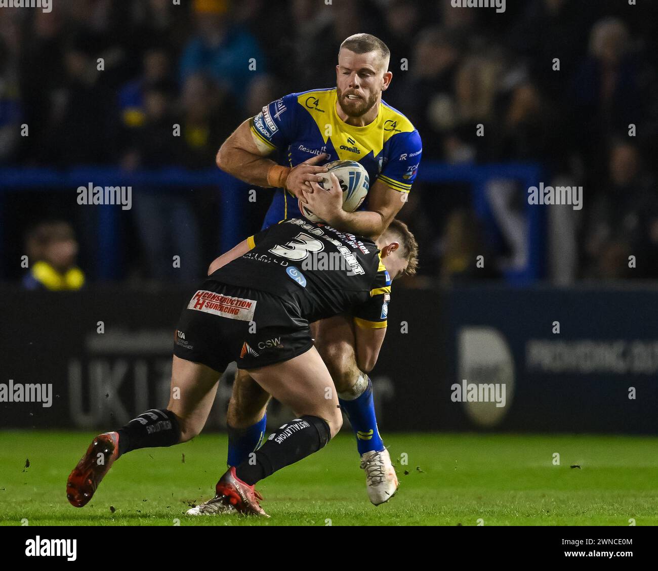 Lachlan Fitzgibbon of Warrington Wolves is tackled by Jack Broadbent of ...